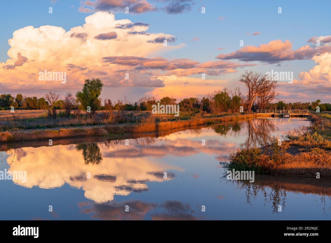 Coloured storm clouds reflected in a still irrigation channel near St ...