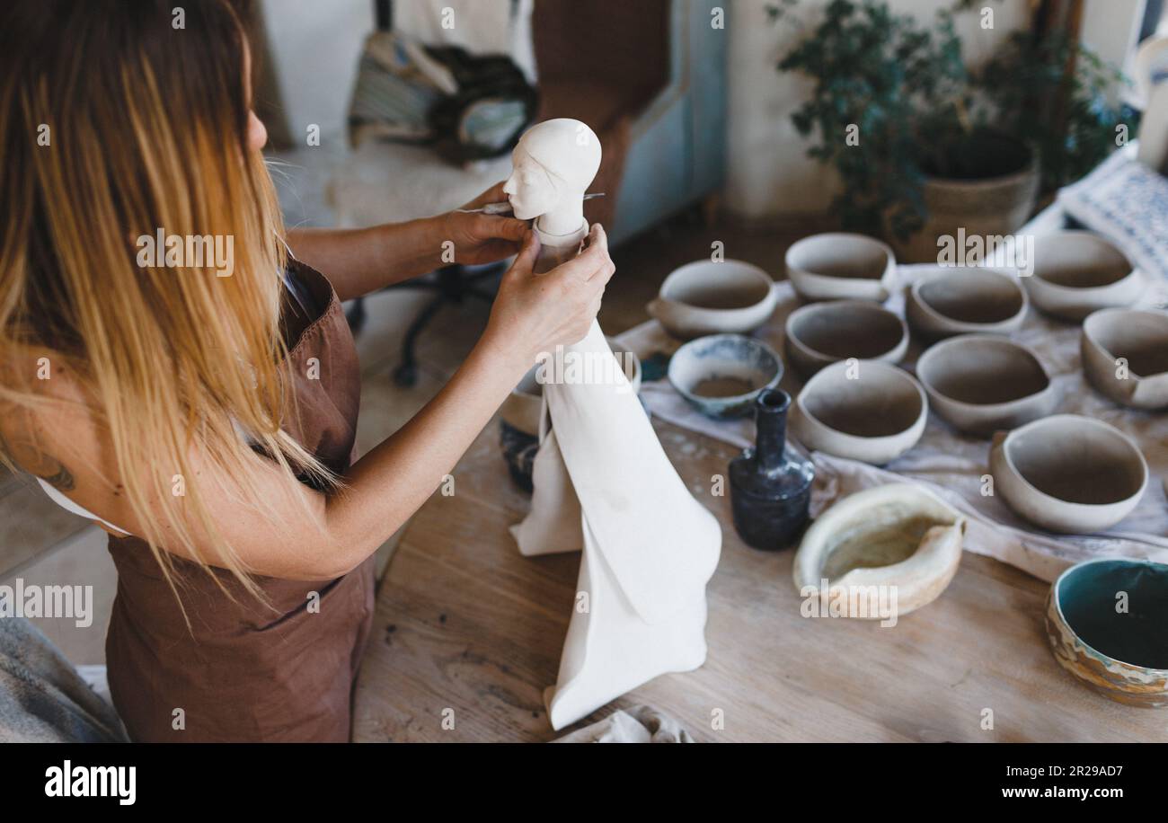 A young woman works in her pottery workshop. Pottery work. Creation of ...