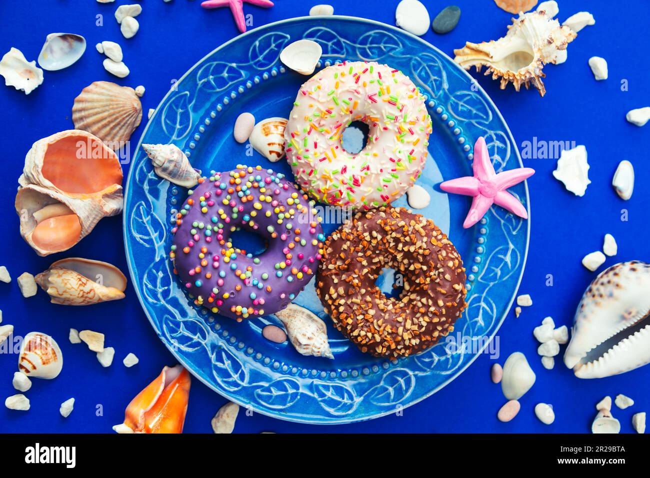 Assorted donuts in a plate on a blue background. Around them are ...