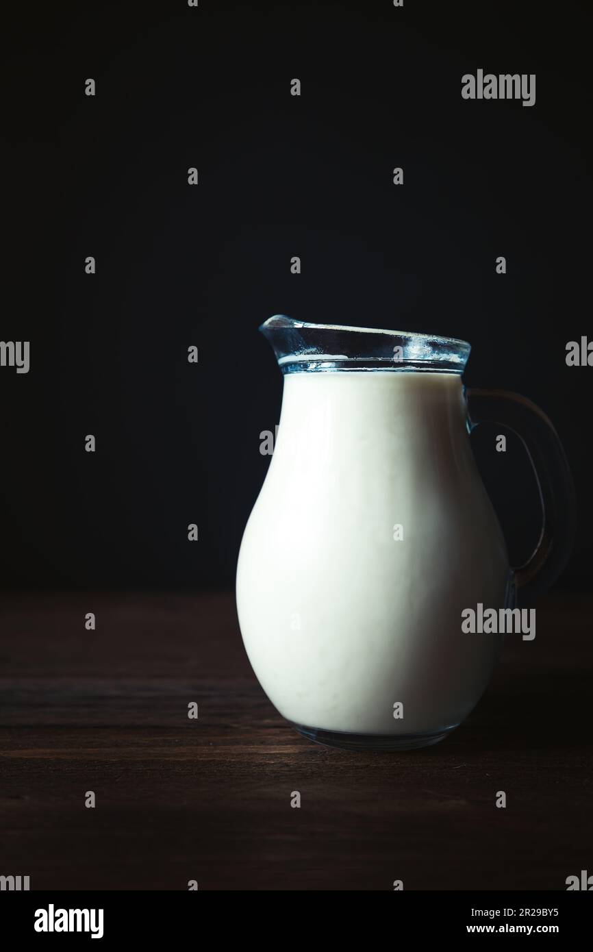 Full jug of milk on the wooden table. Farm product, black background ...