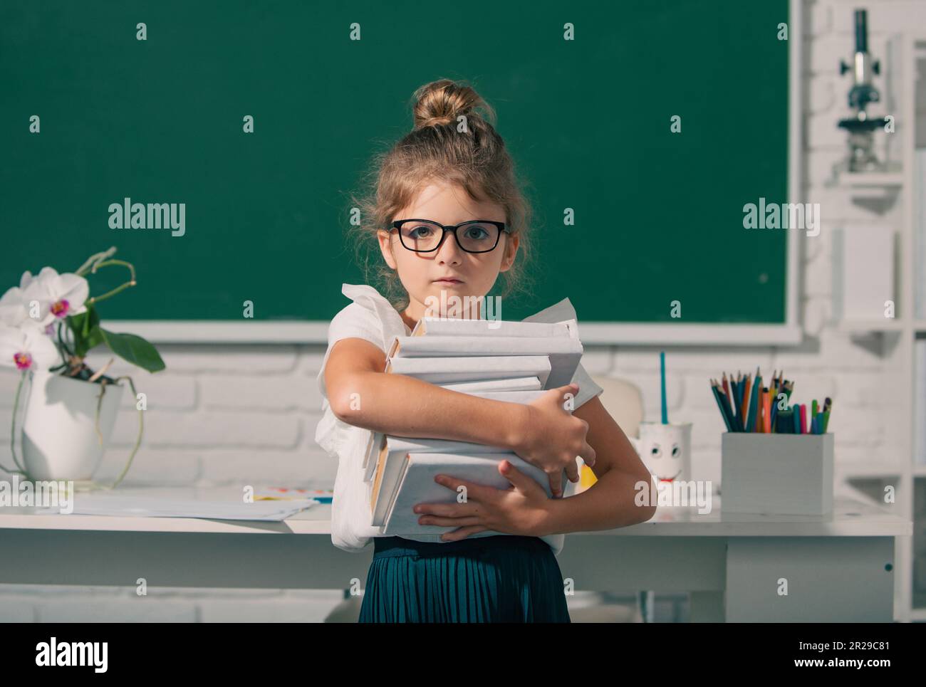 Nerd school girl in glasses with books on blackboard. Kid girl learning ...