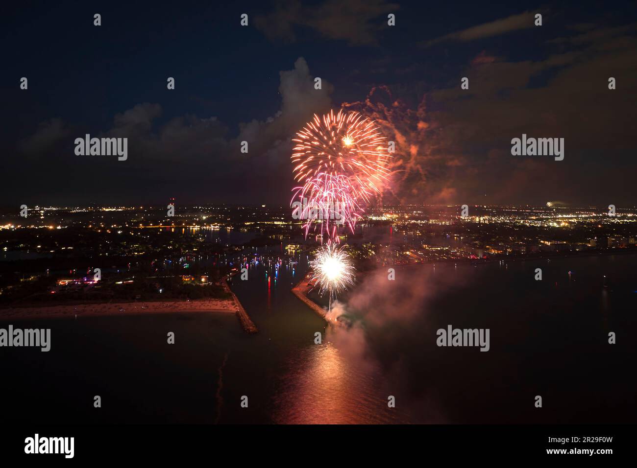 Aerial view of bright fireworks exploding with colorful lights over sea ...