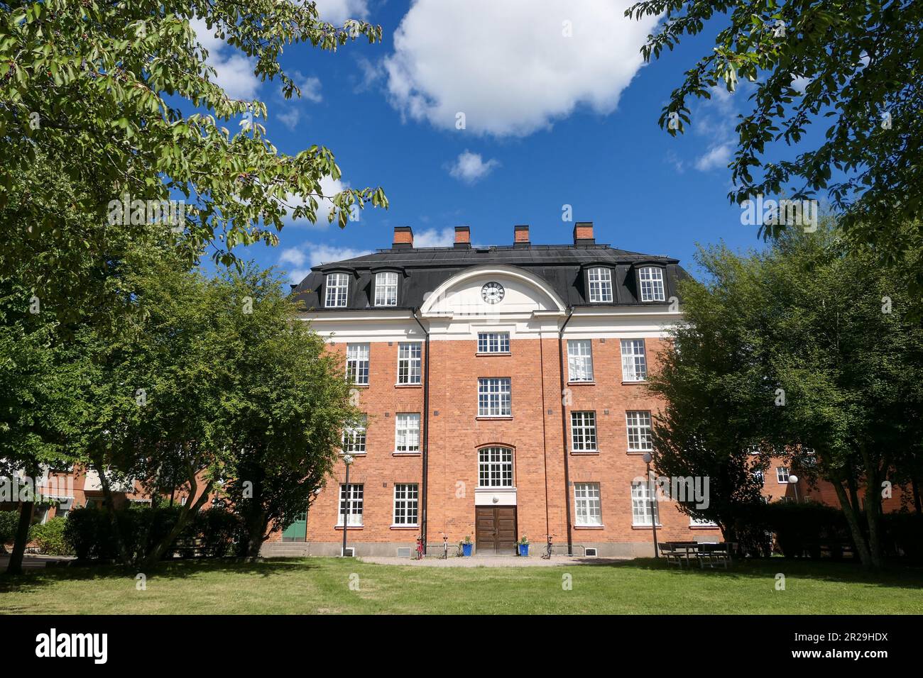 a large brick building with grass and trees Stock Photo - Alamy
