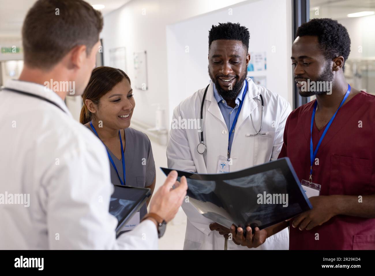 Four happy diverse doctors with tablet and x ray in discussion in ...