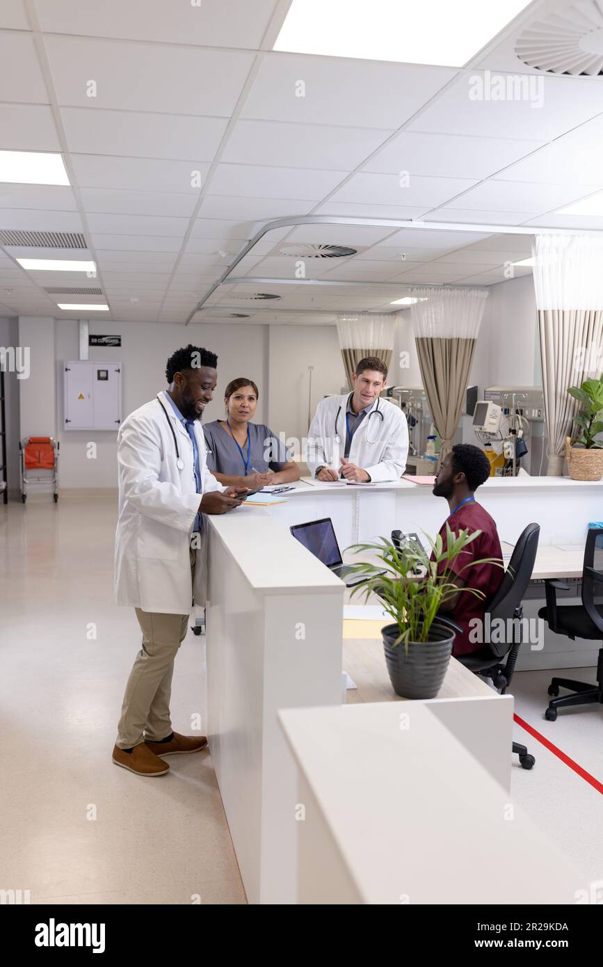 Happy diverse doctors and medical staff talking at reception desk of ...