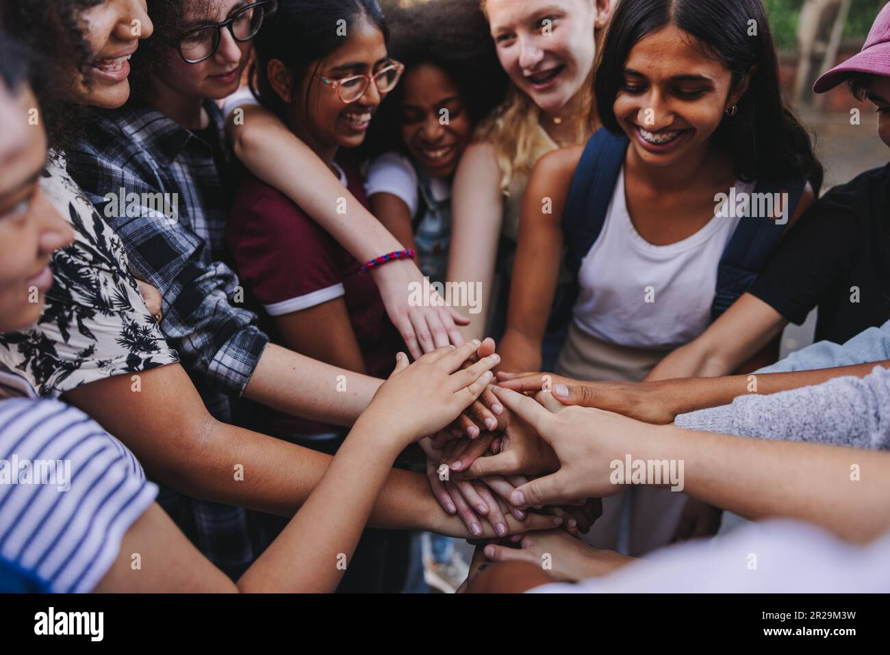 Group of multicultural teenagers smiling cheerfully while putting their ...