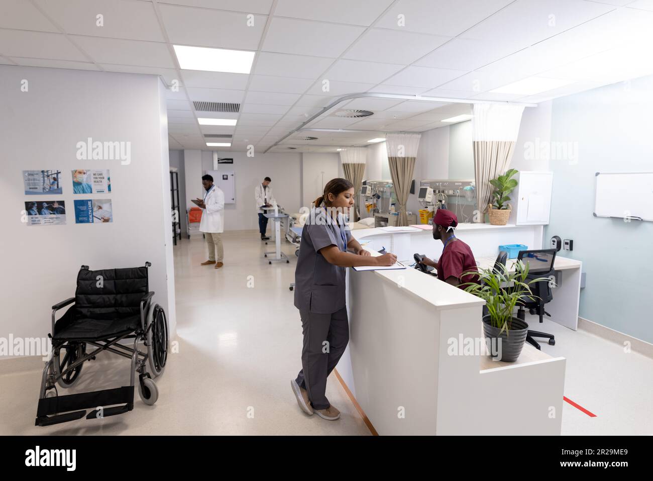 Asian female doctor writing on clipboard at reception desk of hospital ...