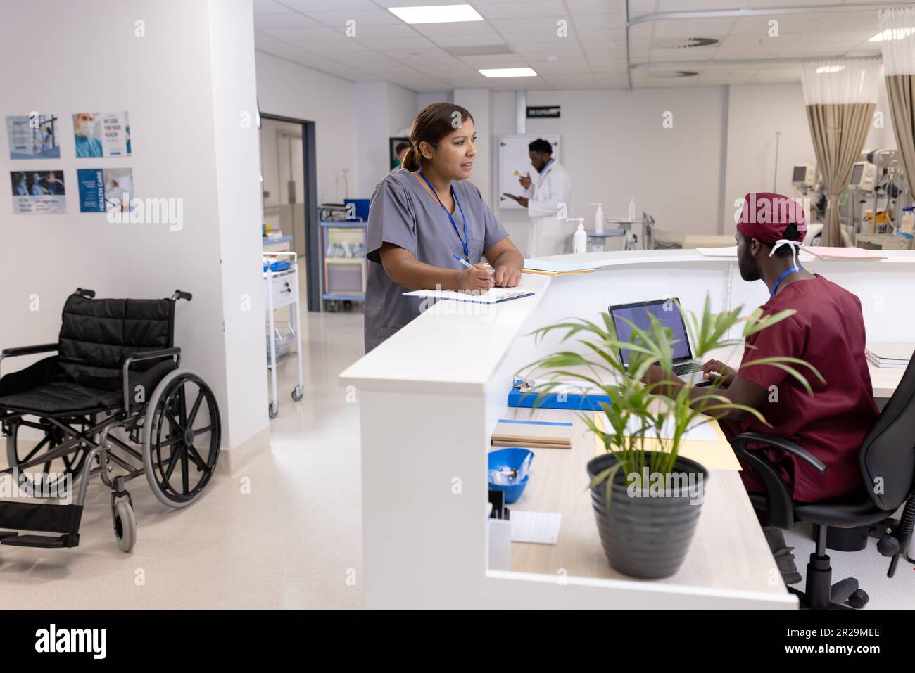 Asian female doctor writing on clipboard at reception desk of hospital ...