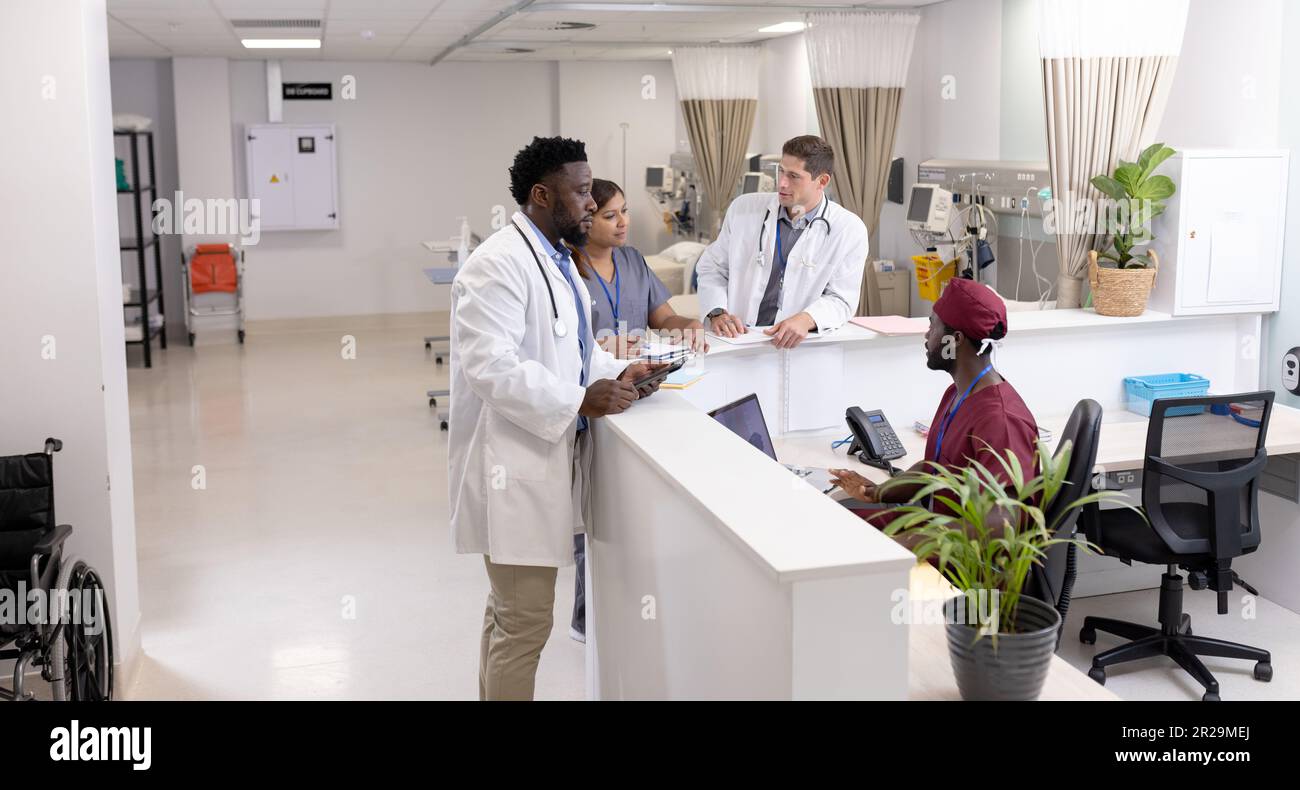 Diverse doctors and medical staff talking at reception desk of hospital ...