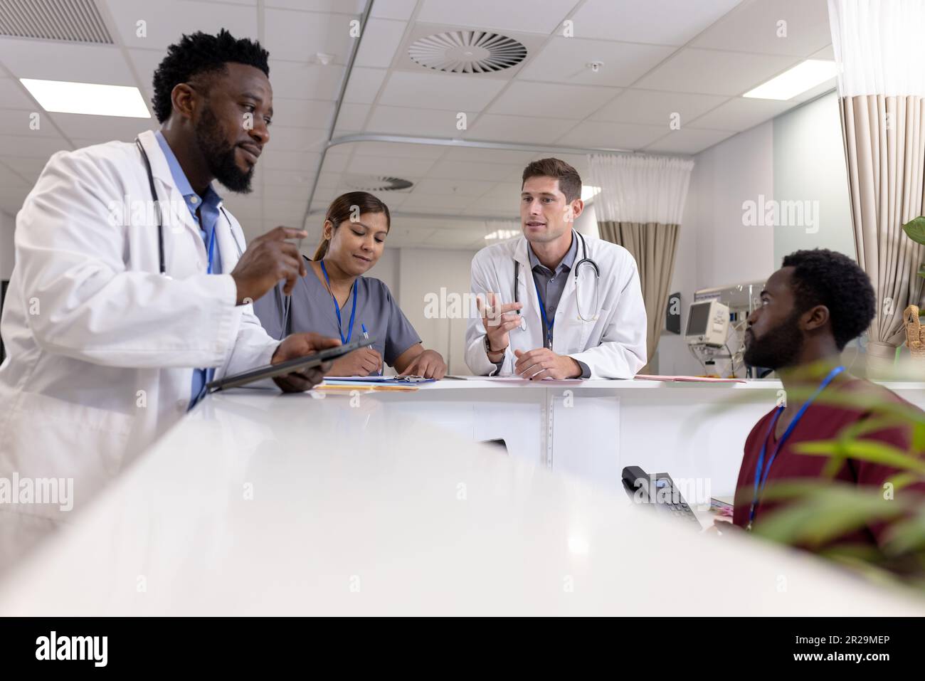 Busy diverse doctors and medical staff talking at reception desk of ...