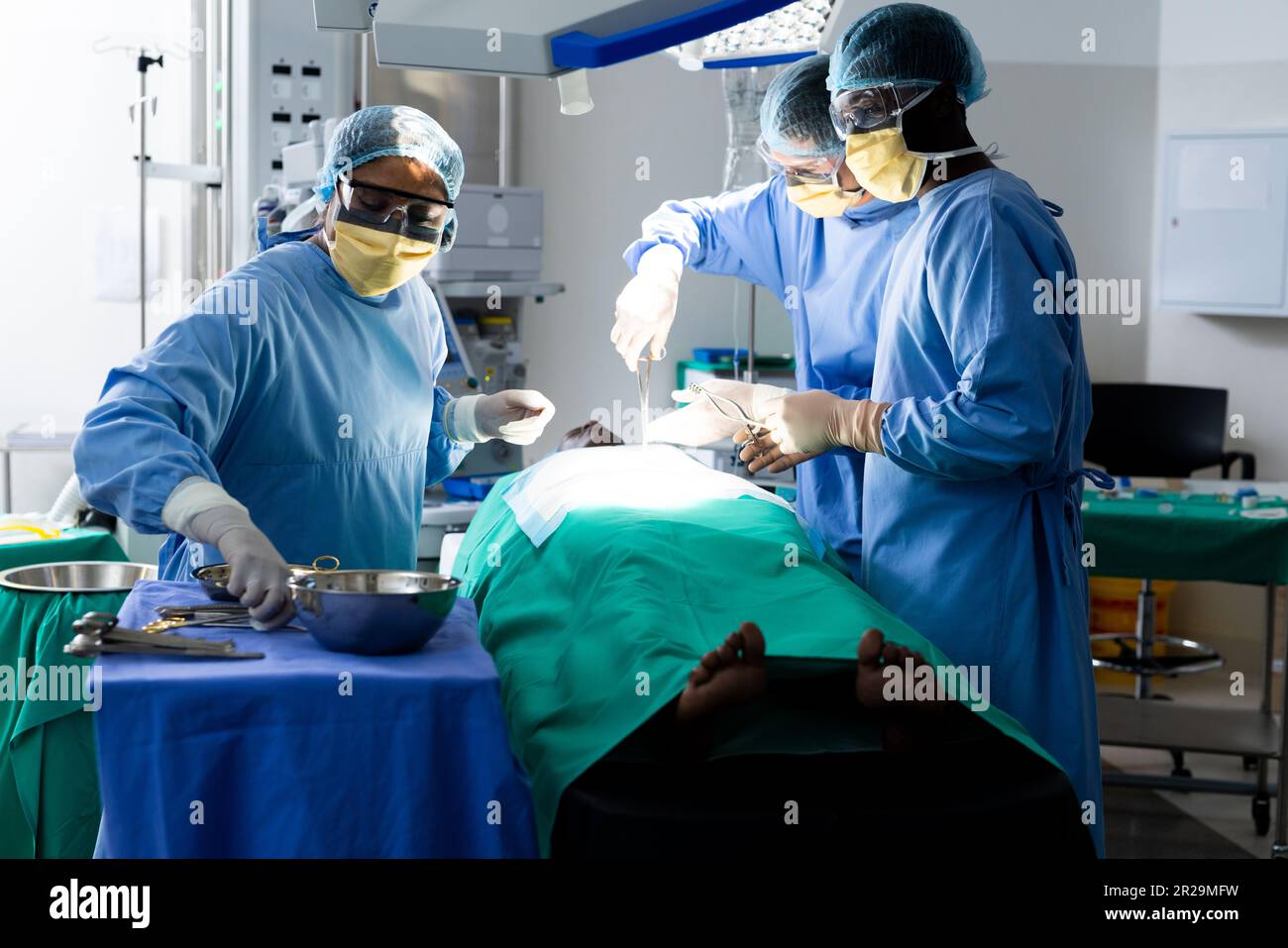 Diverse group of surgeons operating on patient in operating theatre ...
