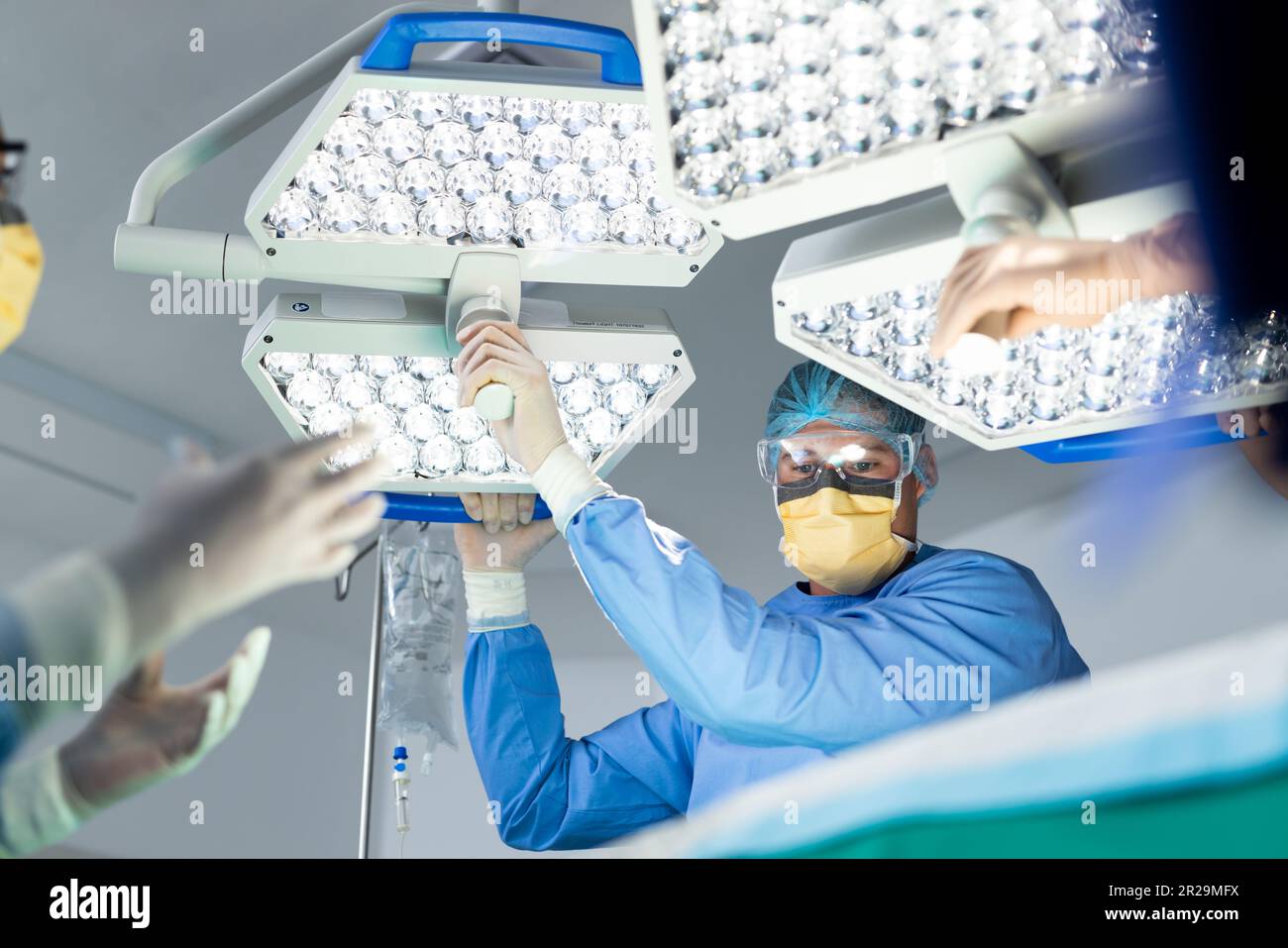 Caucasian male surgeon adjusting light for colleagues in operating ...