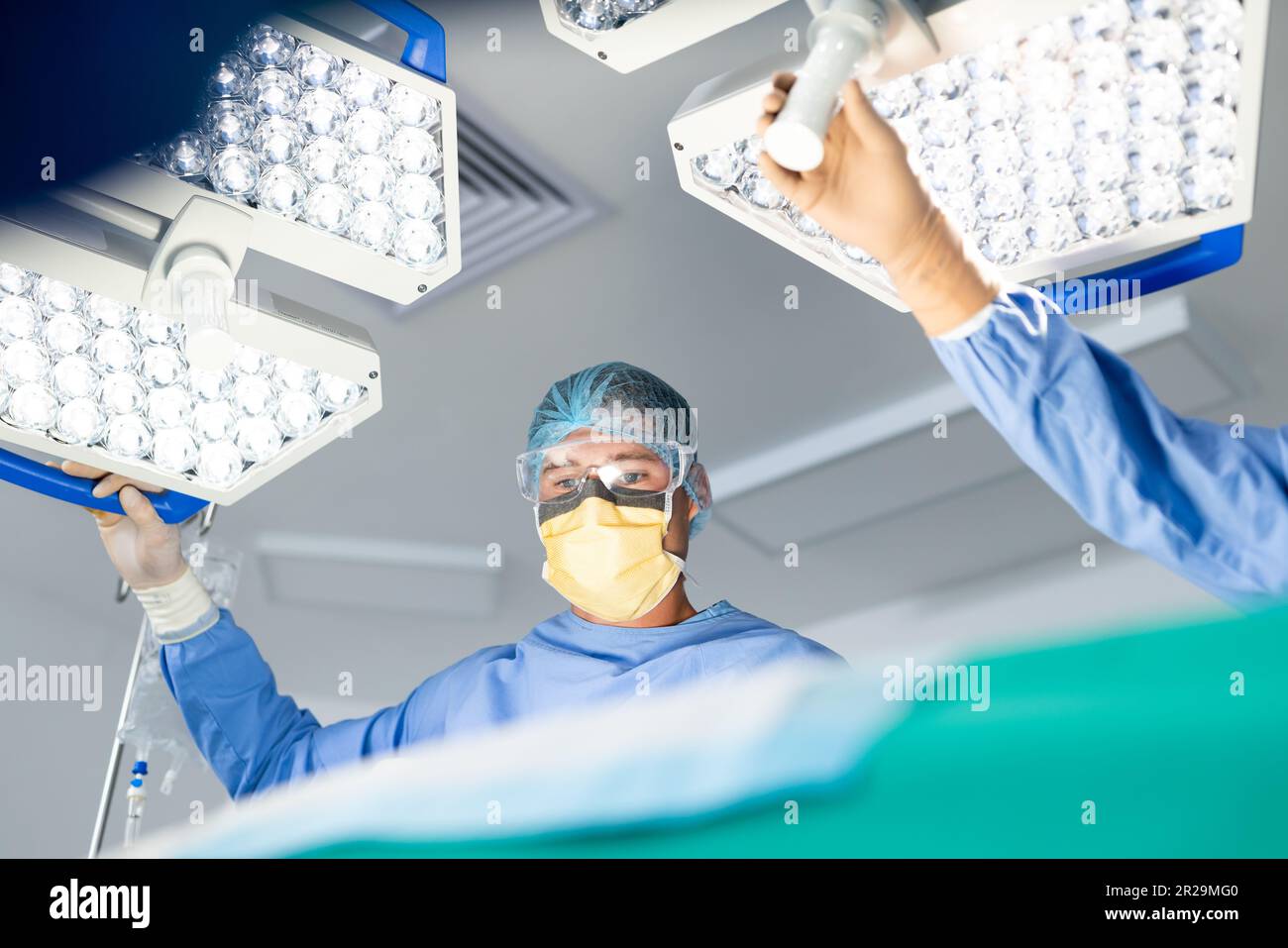 Caucasian male surgeon adjusting lights with colleague in operating ...