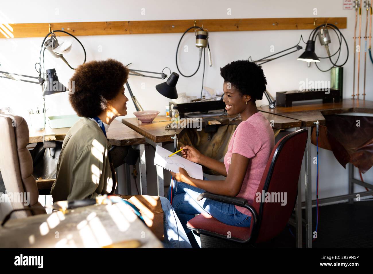 Happy diverse workers drawing sketch and talking, working in jewellery ...