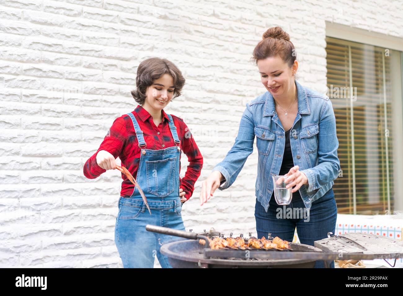 Barbeque party in garden with mom and her daughter at the grill in a ...