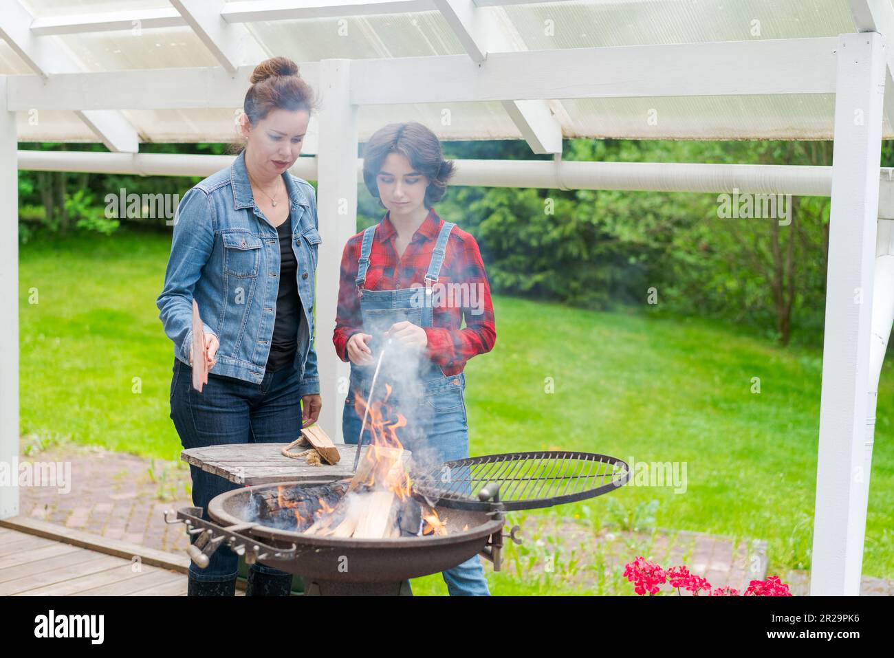 Family barbecue mom and daughter grilling with in a country house ...