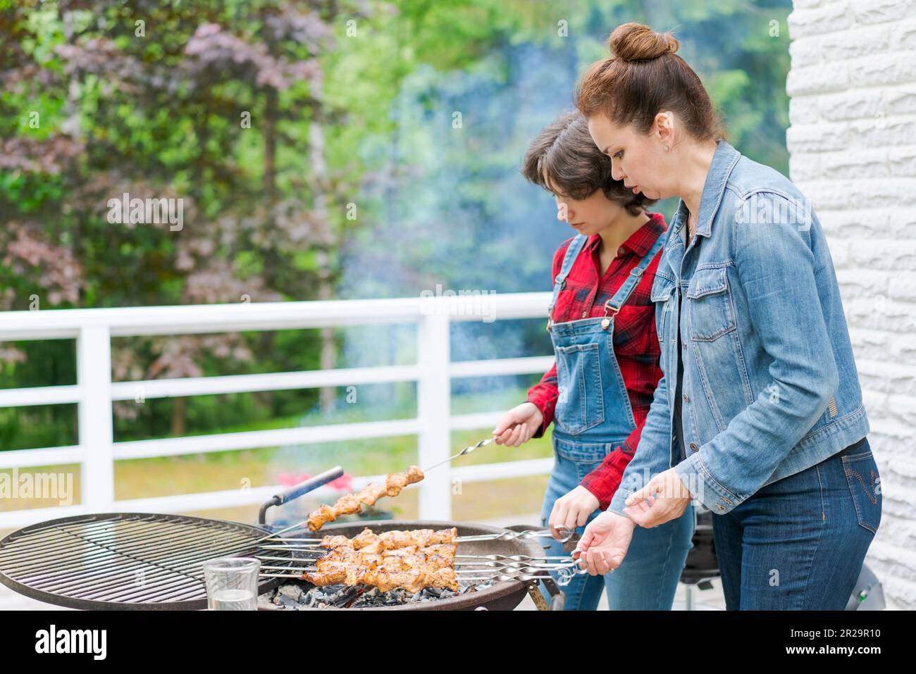Barbeque party in garden with mom and her daughter at the grill in a ...
