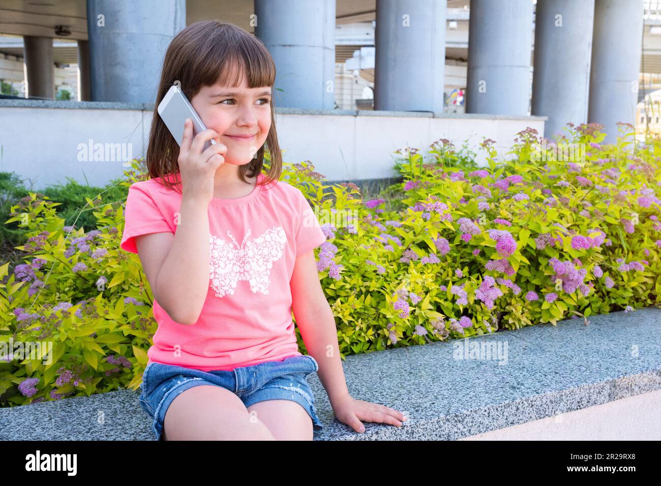Adorable teenager little girl talking phone downtown in city bridge ...