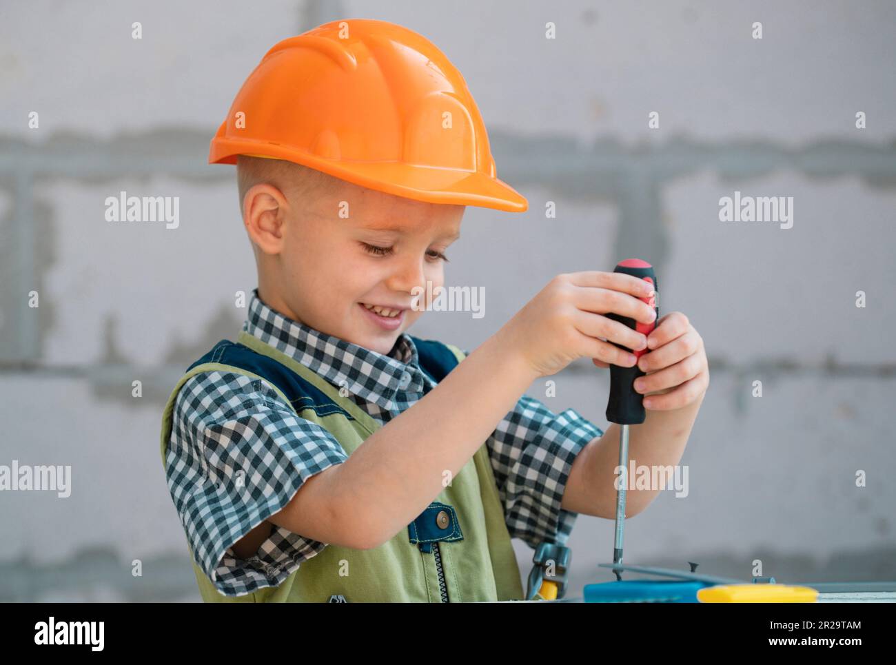 Little boy holding screwdriver. Kid twists bolt with screwdriver ...