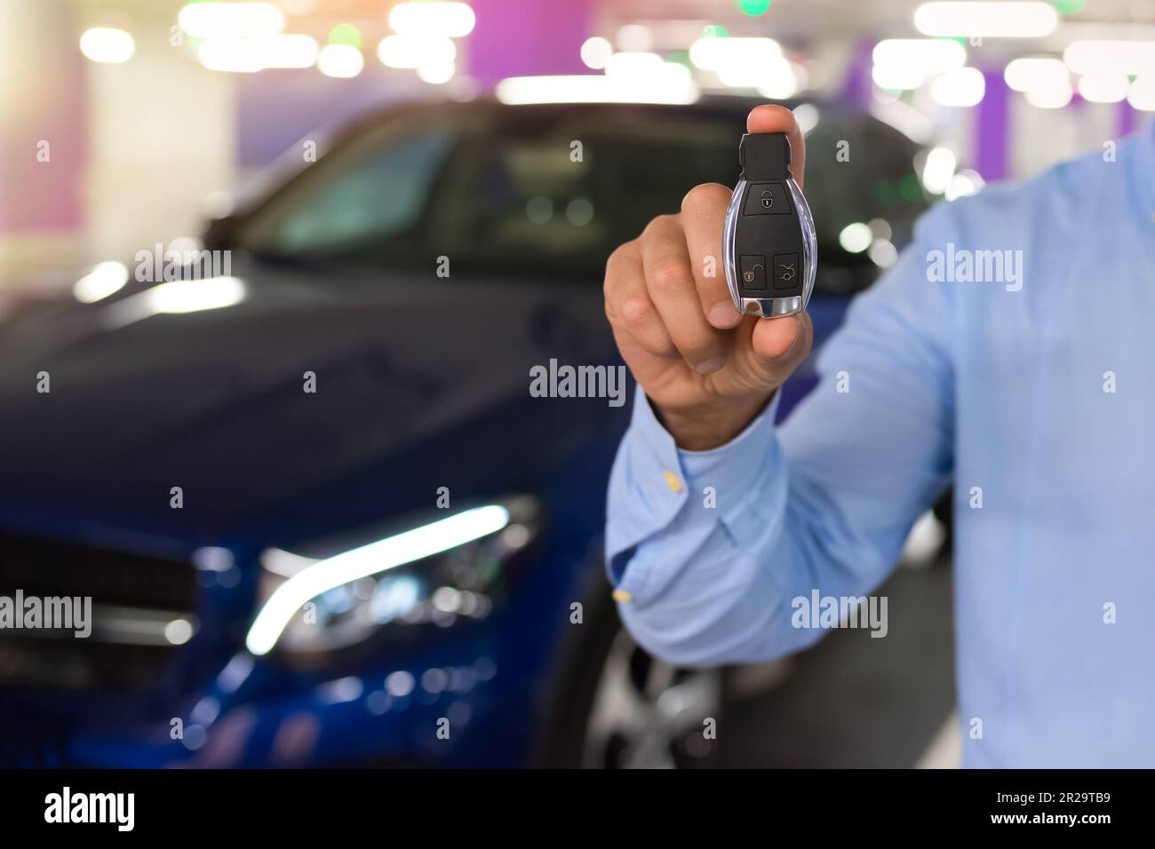 Car Keys. Male hand holding car key, on a parking background Stock ...