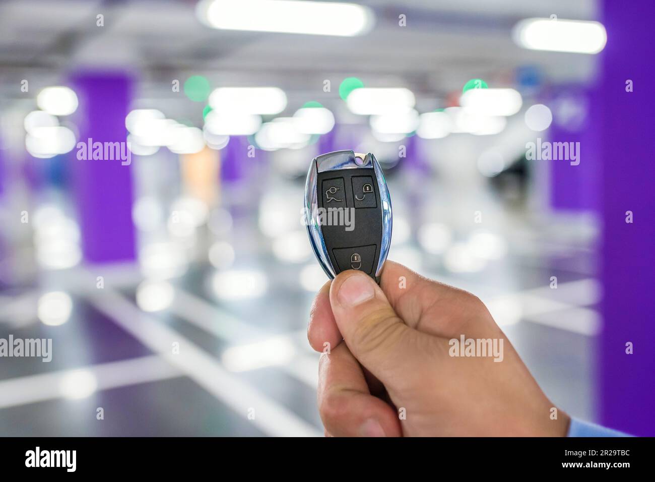 Male hand holding car key, on a parking background Stock Photo - Alamy