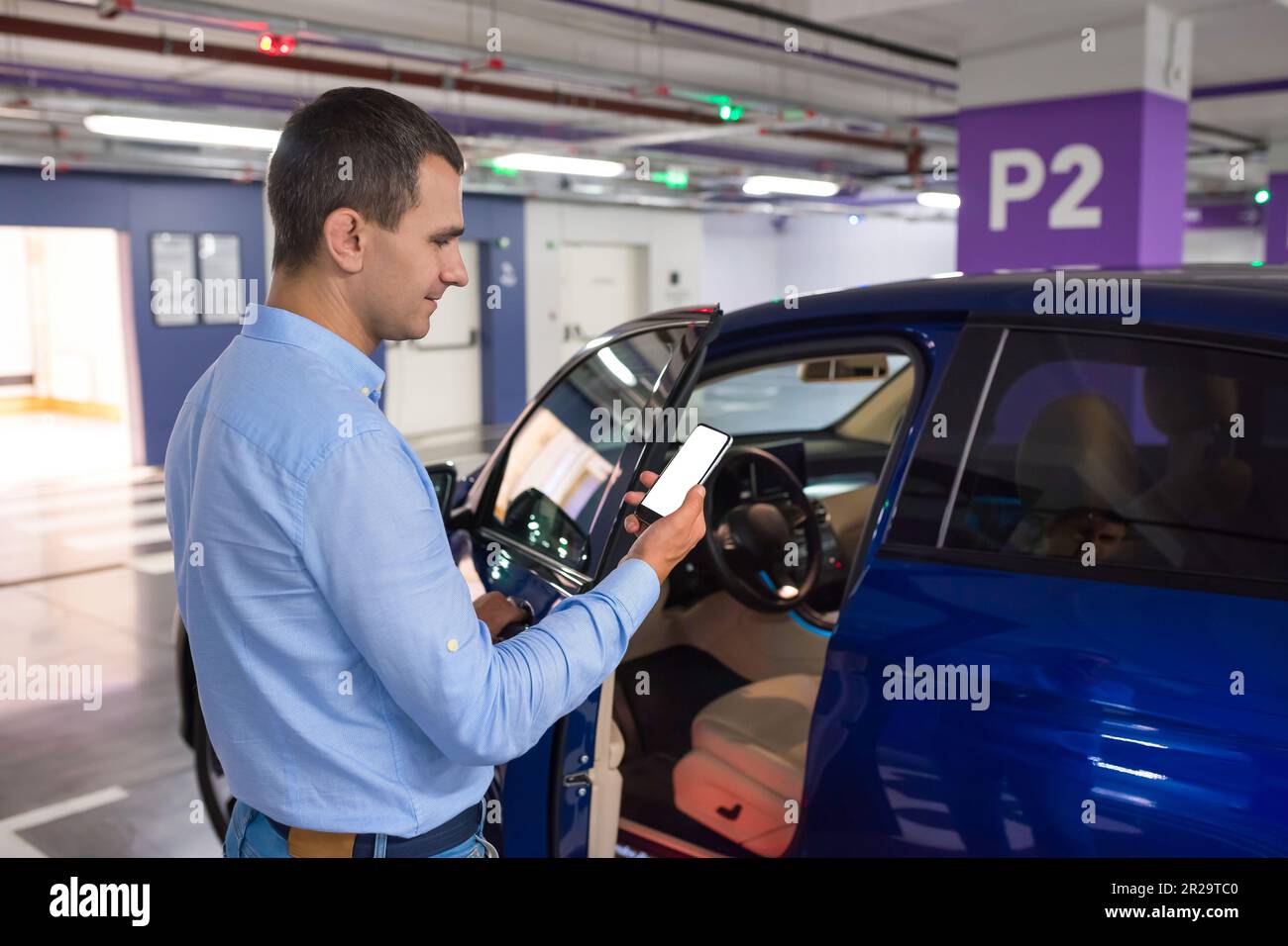 A businessman with a phone in a his hand in an underground parking lot ...