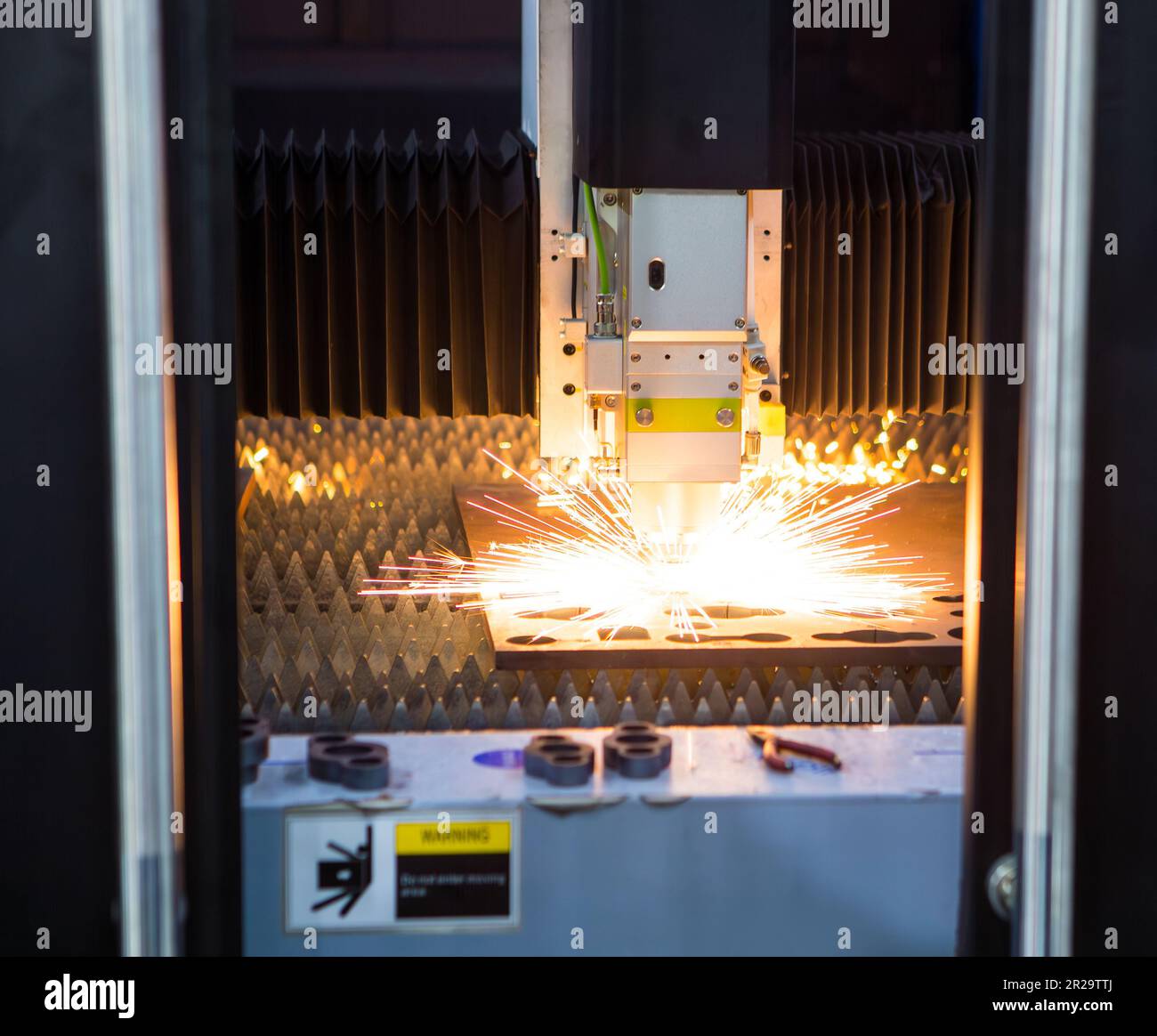 CNC fiber laser cutting machine cutting metal sheet with flying sparks ...