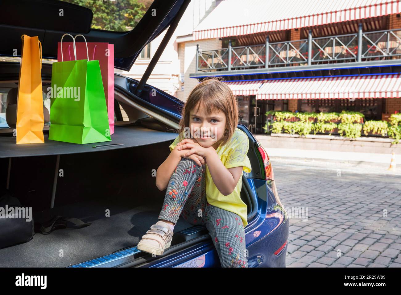 The child with packages sits in a luggage carrier and waits for parents ...