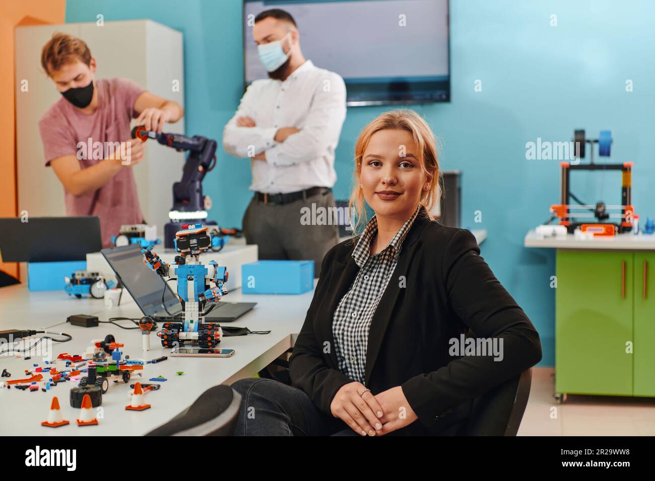 A woman sitting in a laboratory while her colleagues test a new robotic ...