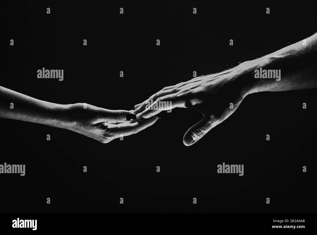 Two hands stretch each other, black background. Couple in love holding ...