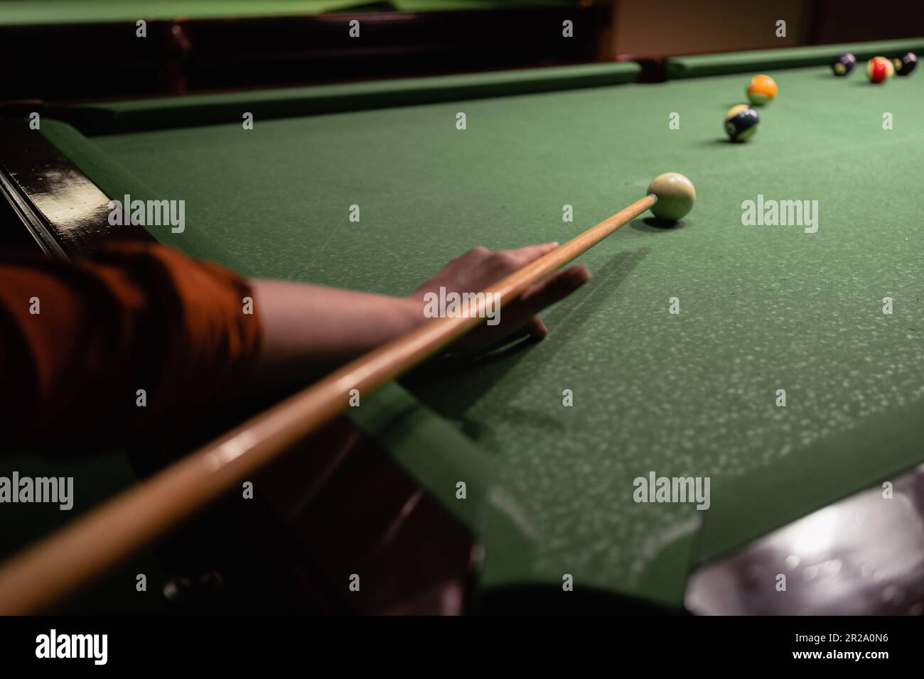 Playing billiards. Female hand with cue aiming on billiard ball at ...