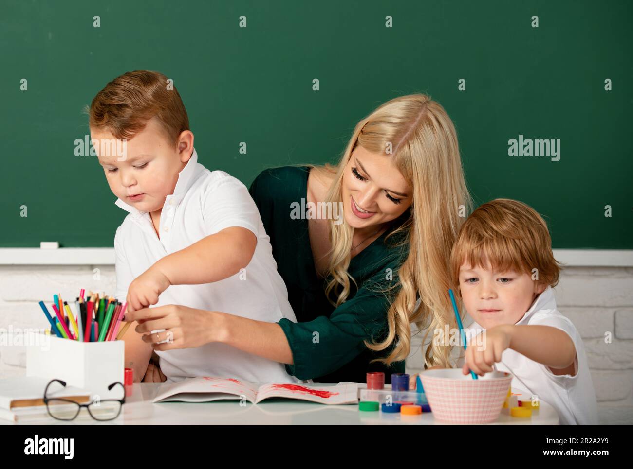 Little children with kindergarten teacher drawing at table indoors ...