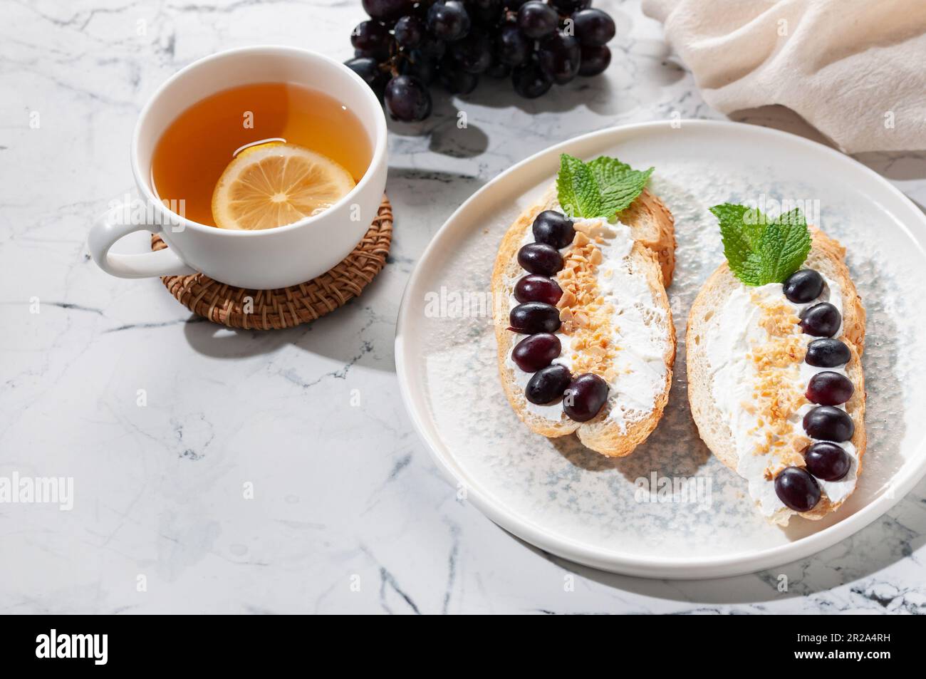 An appetizer of a sandwich with cheese, grapes, nuts and mint greens ...