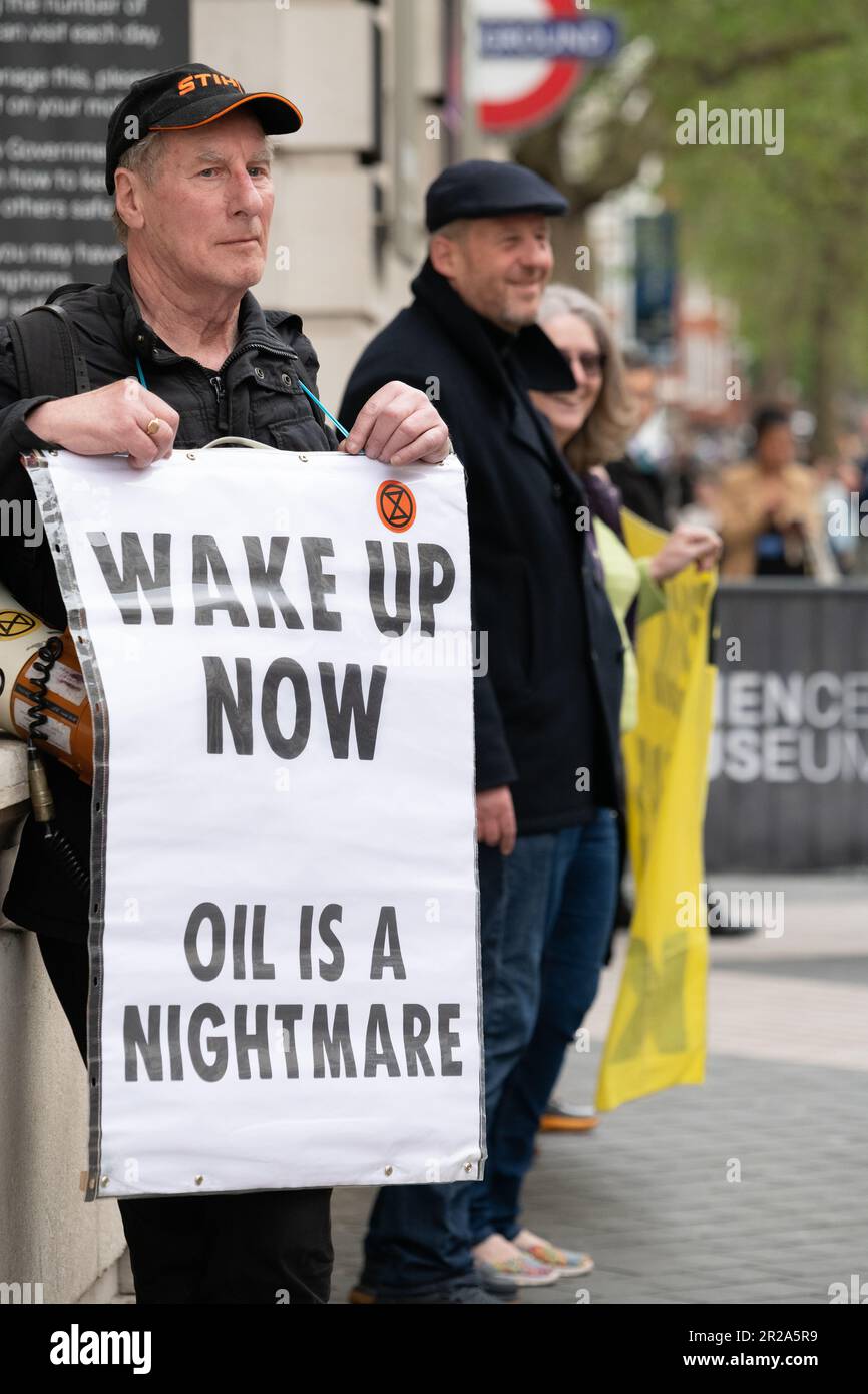 A climate activist holds a banner saying "Wake Up Now - Oil Is A ...