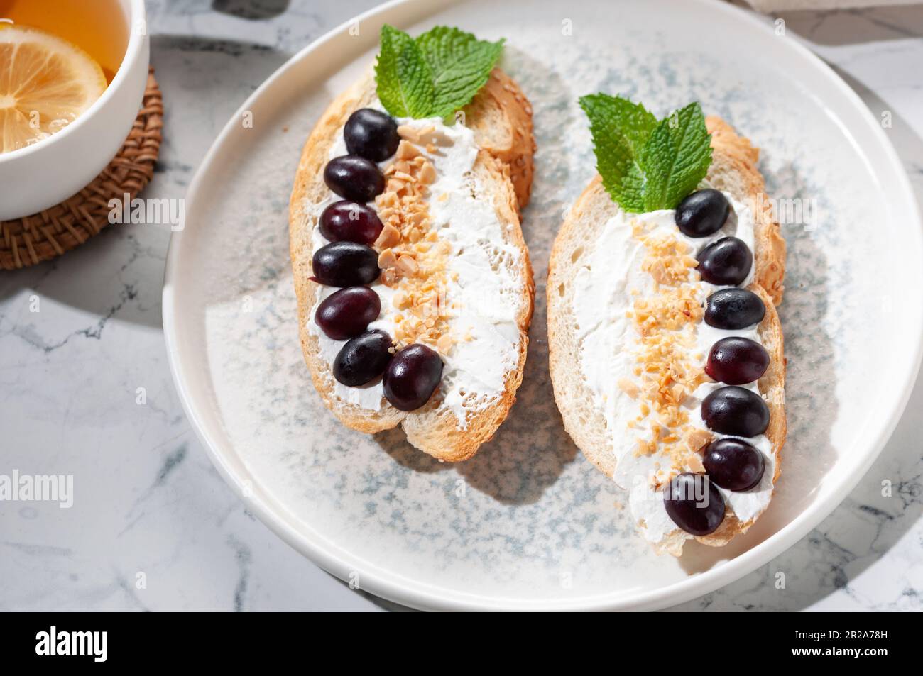 An appetizer of a sandwich with cheese, grapes, nuts and mint greens ...