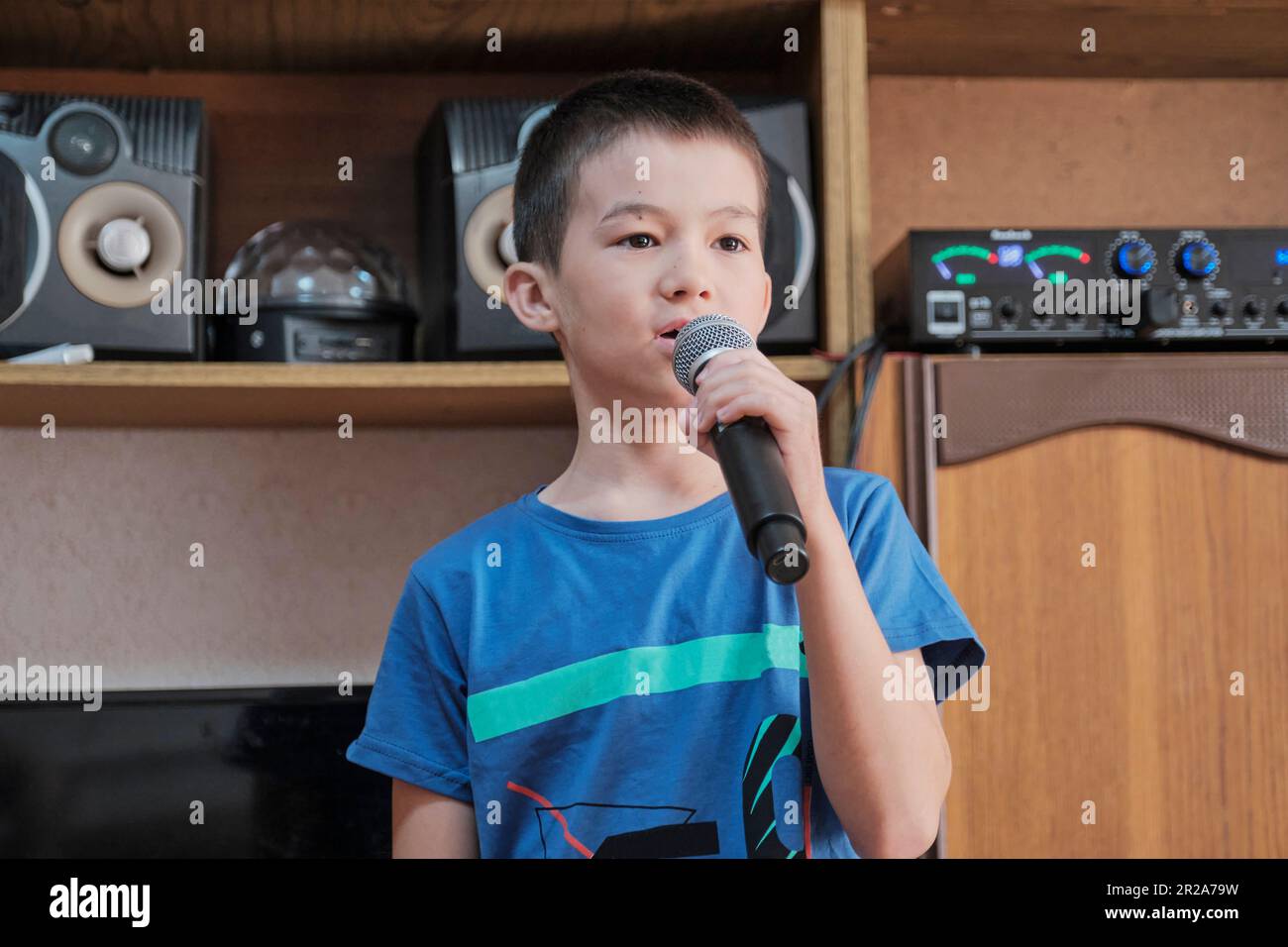 Asian boy holding microphone singing karaoke at home concert. Children ...
