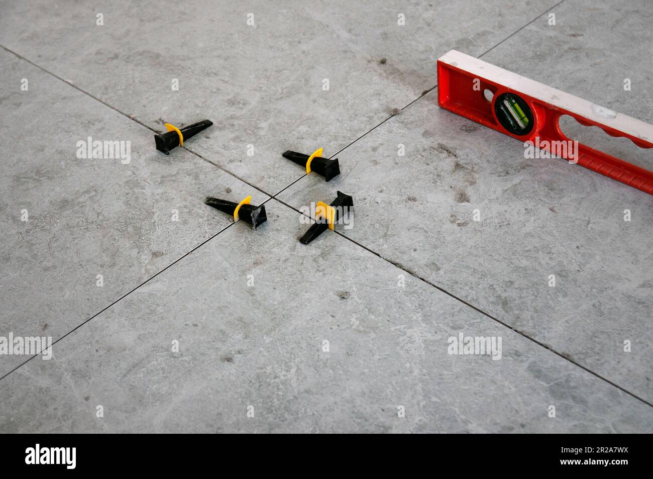 The process of laying tiles on the floor using tools and fixtures. Gray ...