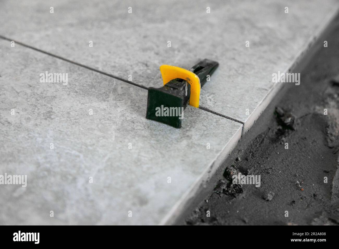 The process of laying tiles on the floor using tools and fixtures. Gray ...