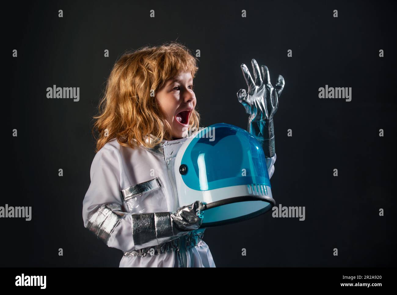Cute little boy spaceman child in space suit holding helmet on black ...