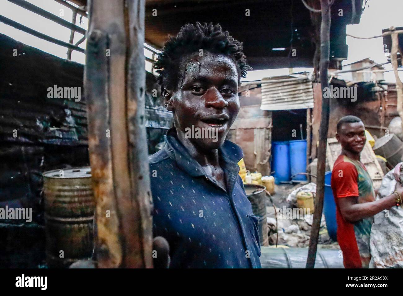 Workers poses at a brewing store in Kibera Slum. Nairobi residents walk ...
