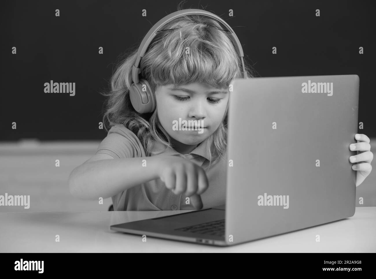 Cute boy wearing headphones, study with laptop in classroom, listening ...