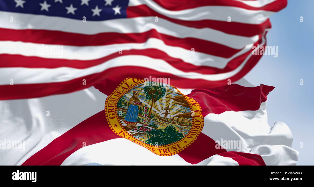 The flags of Florida and United States waving in the wind on a clear ...