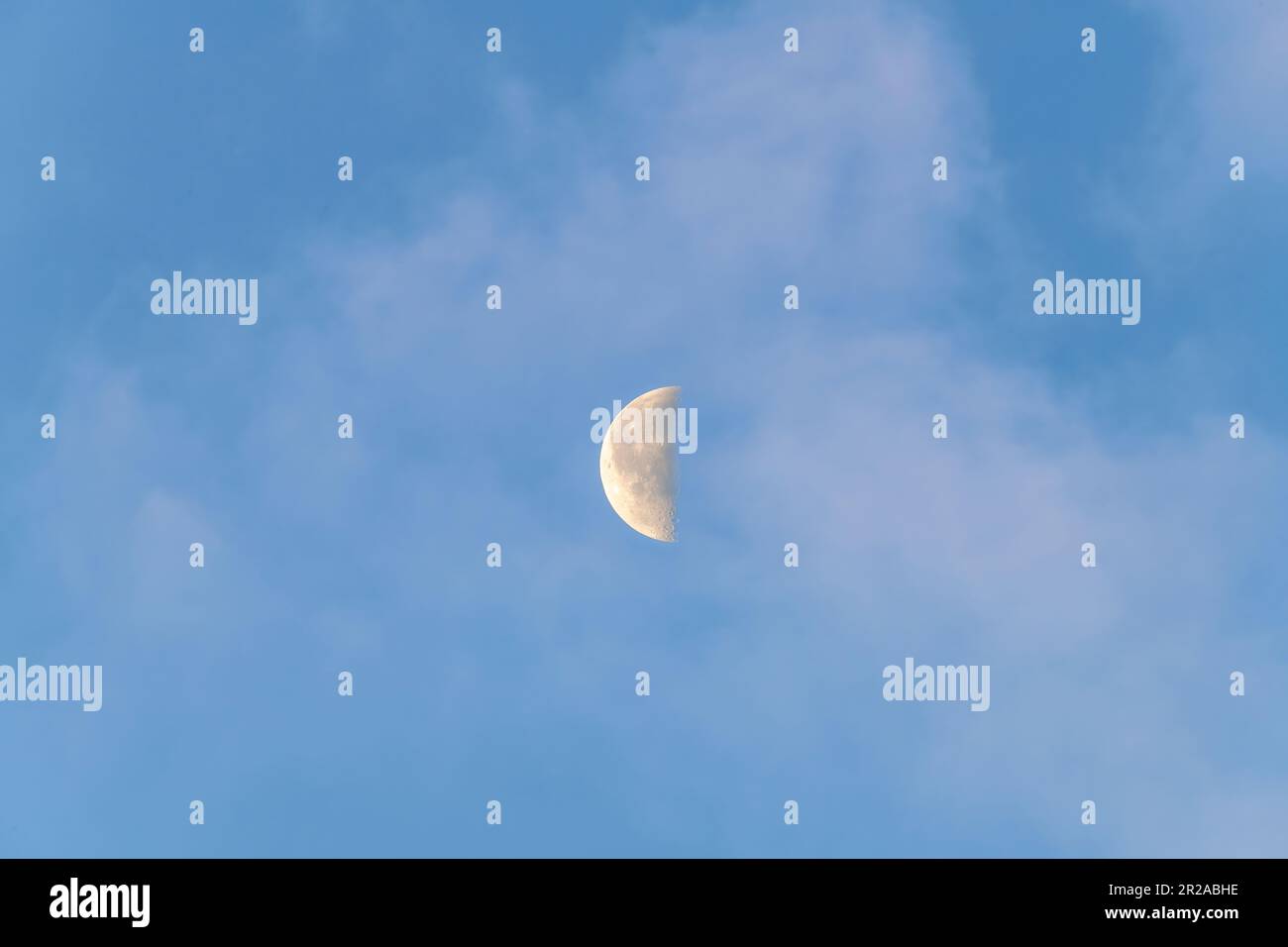 Close up of a bright illuminated half-moon during daylight in a blue ...
