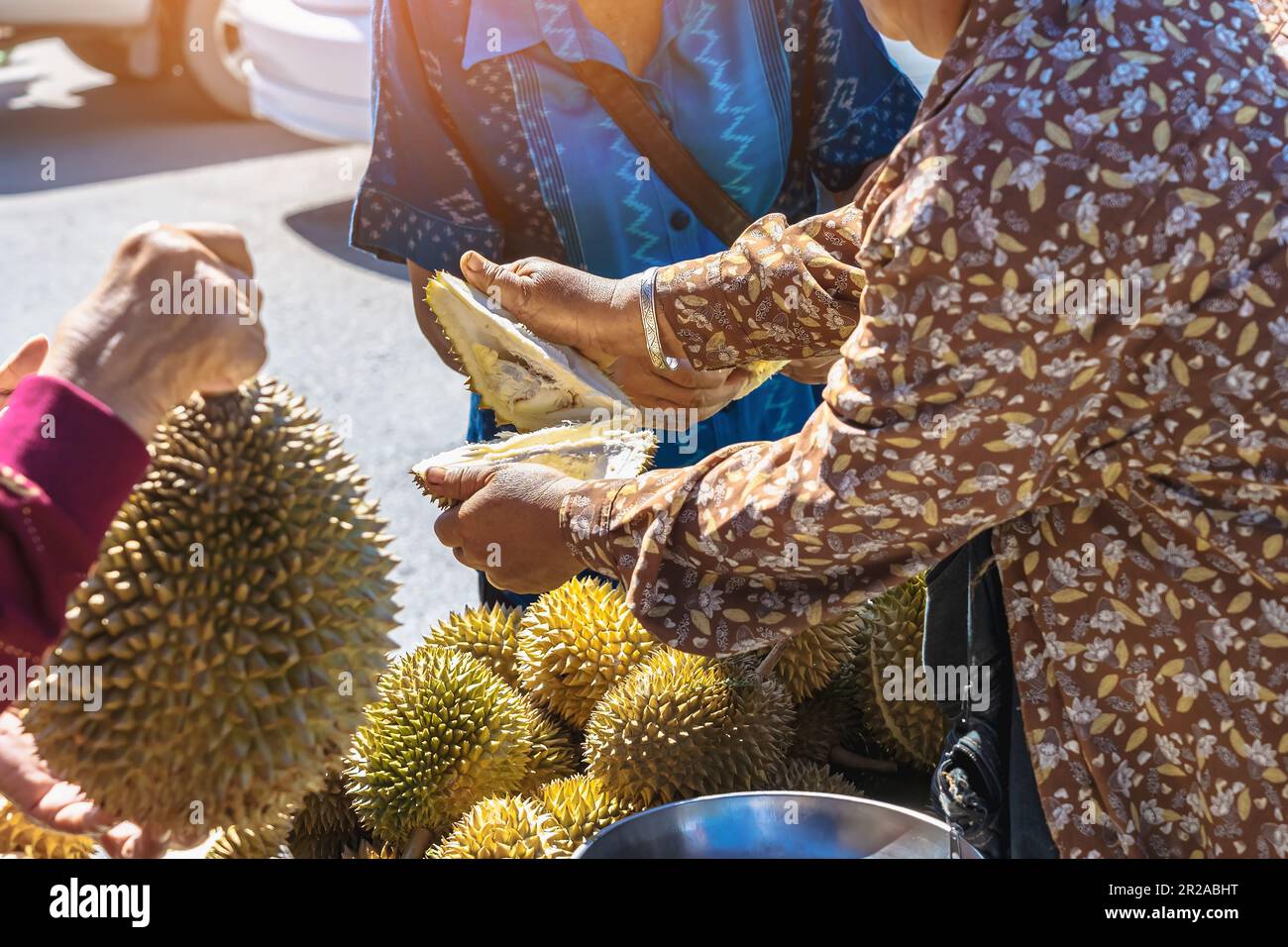 Elderly Thai female vendor ride motorcycle selling durians and fruits ...