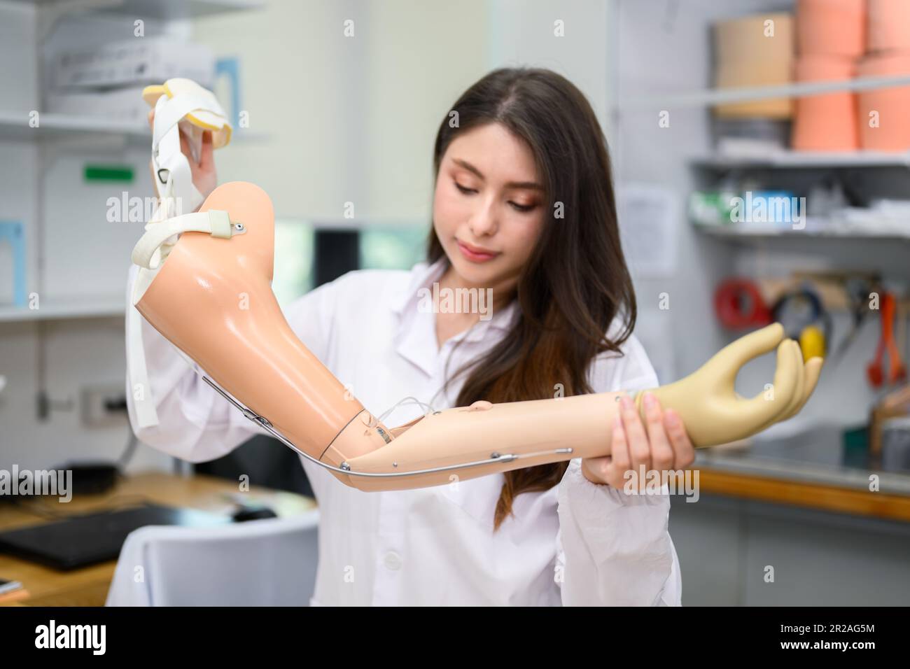 Female technician assembling and fixing parts of modern prosthetic arm ...