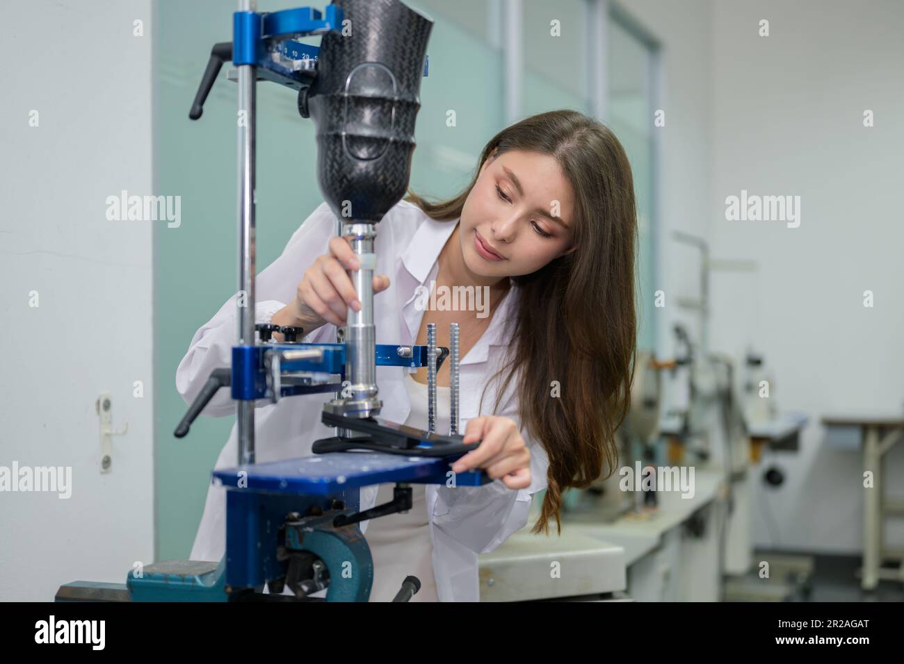 Female technician assembling and fixing parts of modern prosthetic leg ...