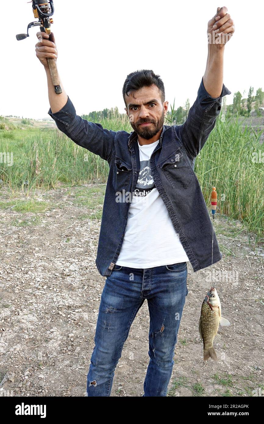 A fisherman is seen holding fish he caught at Tigris river. In ...