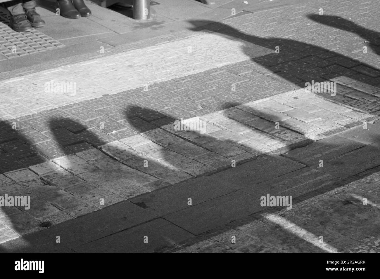 Shadows of people waiting to move forward to cross a street at a ...