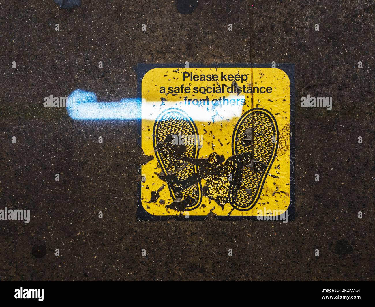 A worn social distancing sticker on the floor of a platform in the ...