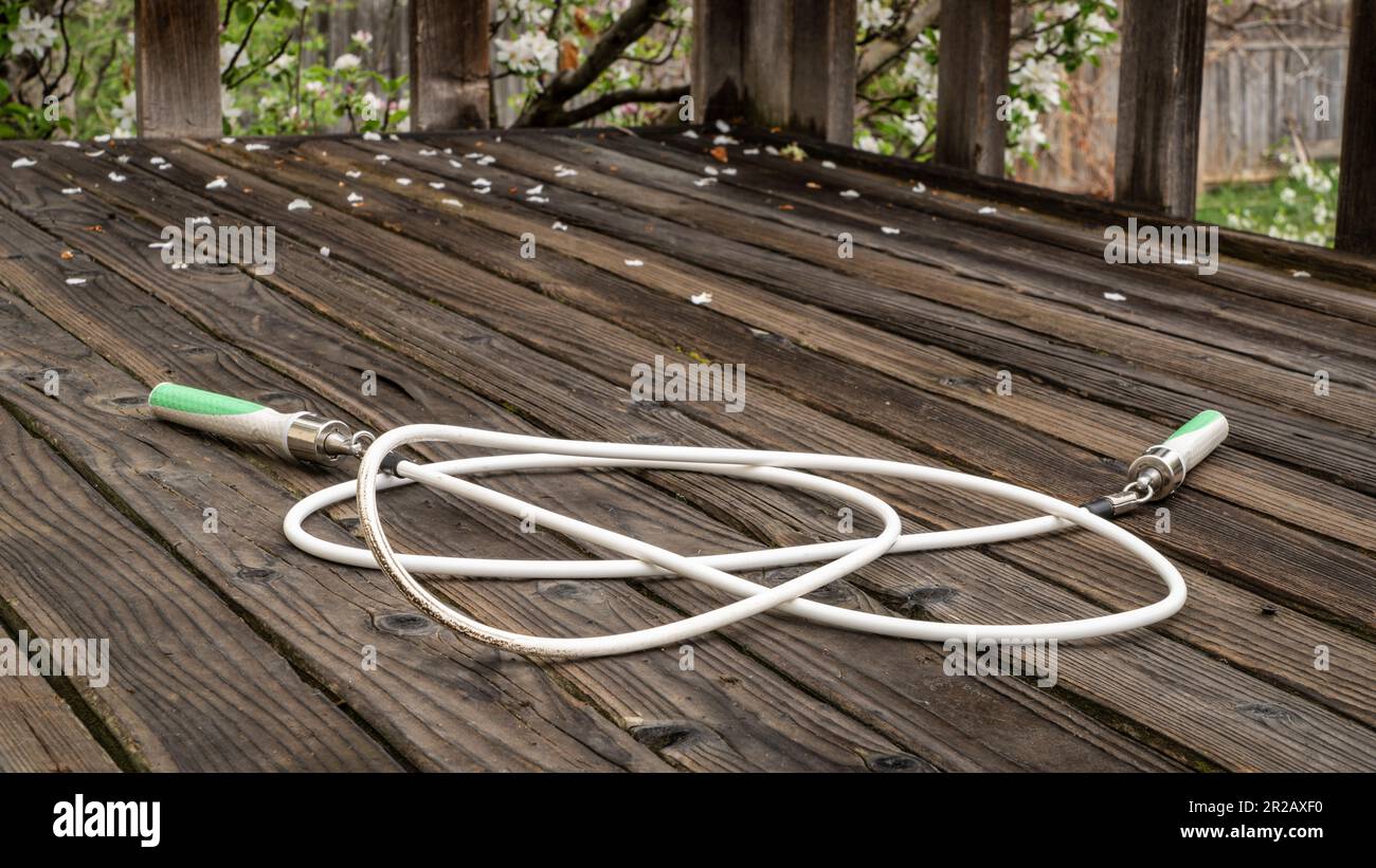 heavy fitness jump rope on a rustic, weathered wooden backyard deck in springtime scenery Stock ...